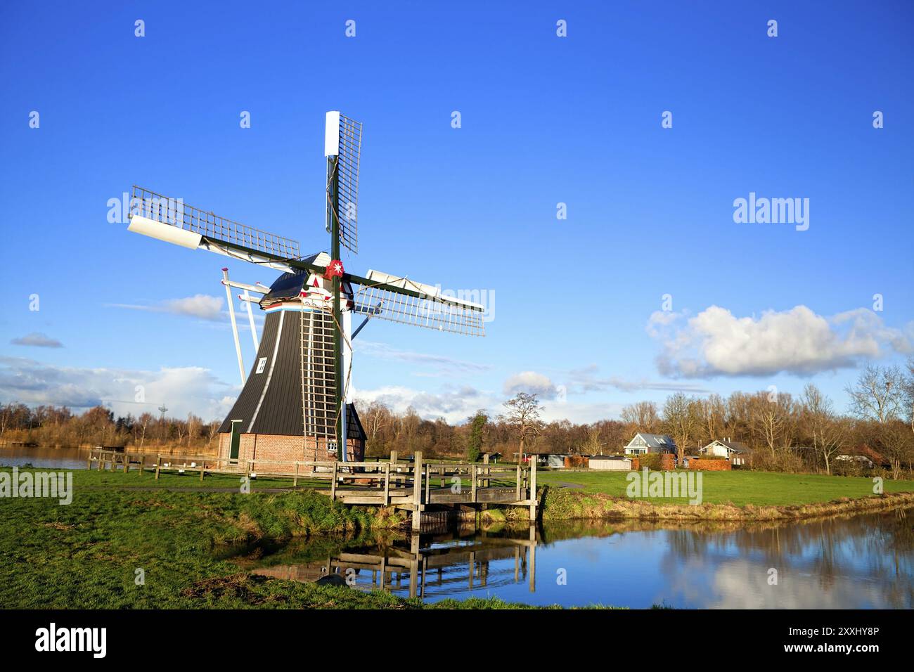 Dutch wooden windmill by lake over blue sky Stock Photo - Alamy