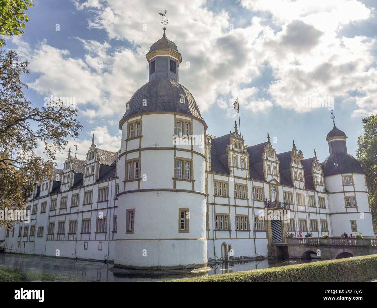 Large, white castle with towers and moat on a sunny day with bright sky ...
