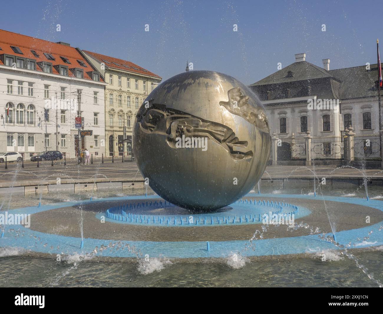 Spherical statue in a fountain in front of historical buildings with ...
