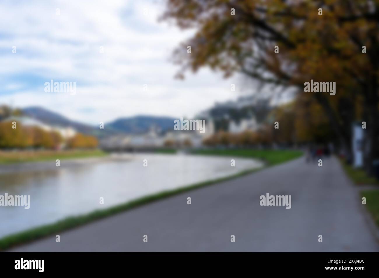 A blurred image of a river with a pathway running alongside it. The ...