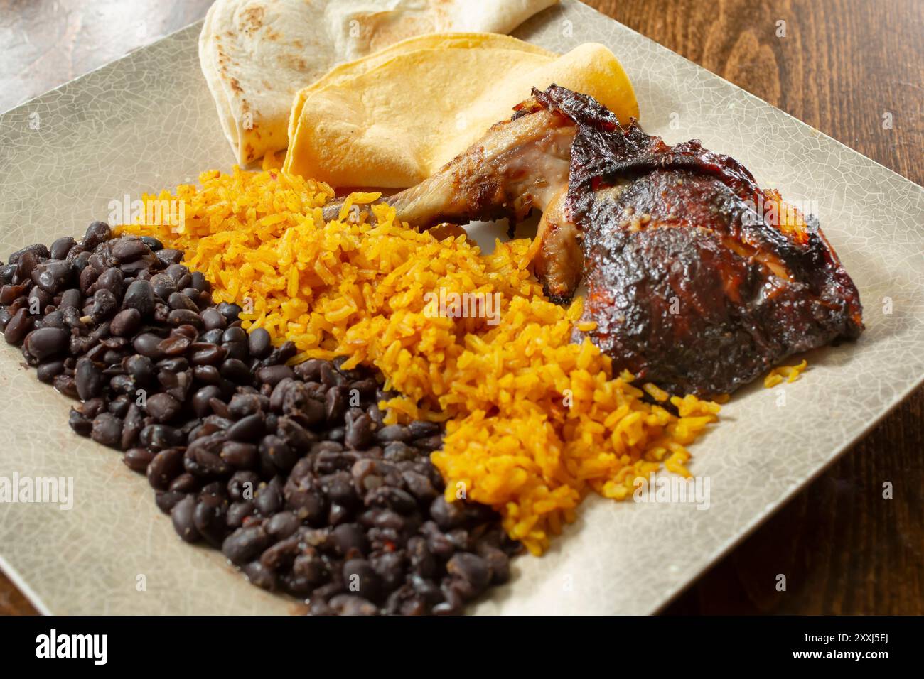 A view of a plate of a rotisserie chicken quarter with rice and beans ...