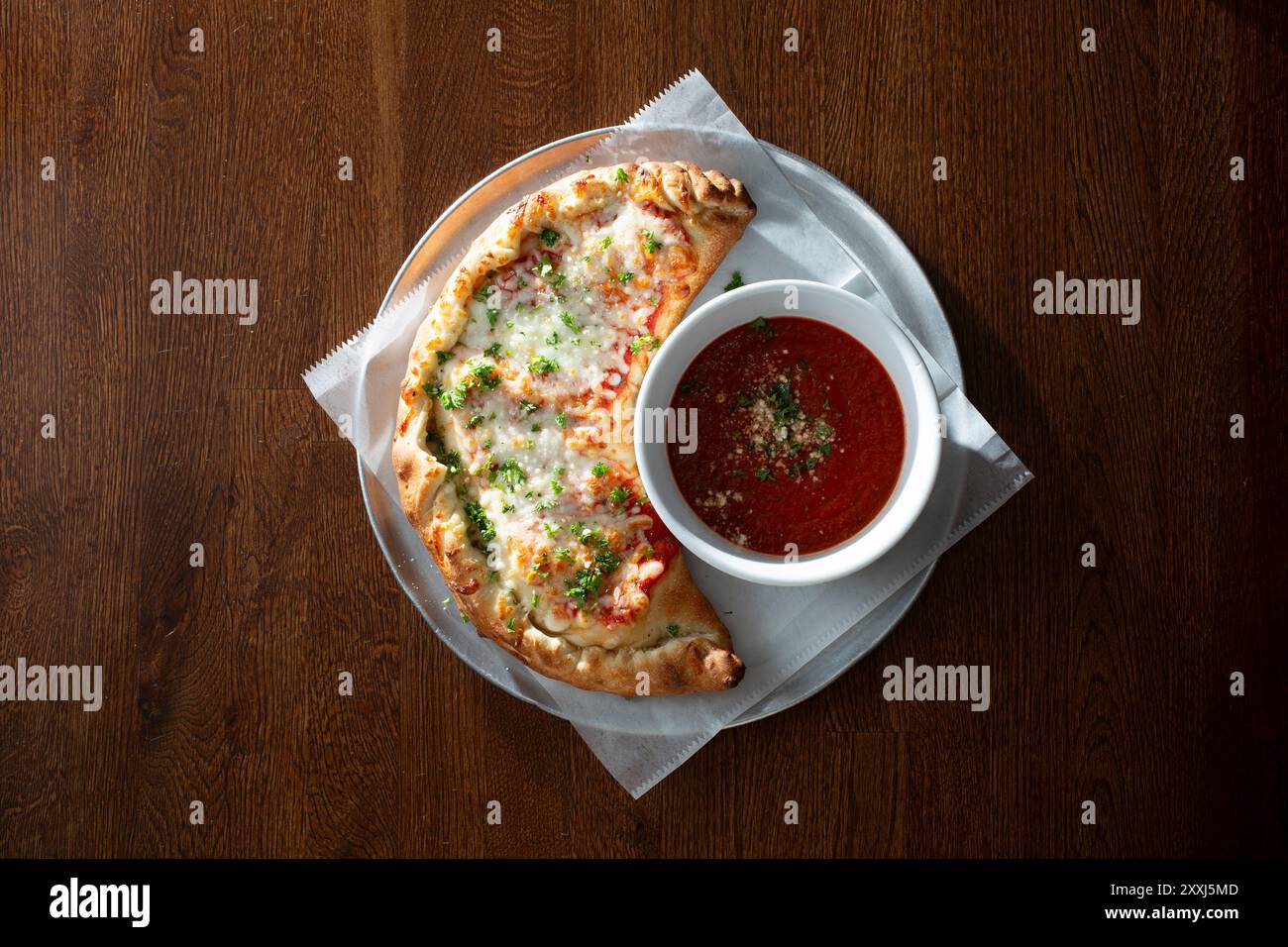 A top down view of a calzone entree, with a side of marinara dipping ...