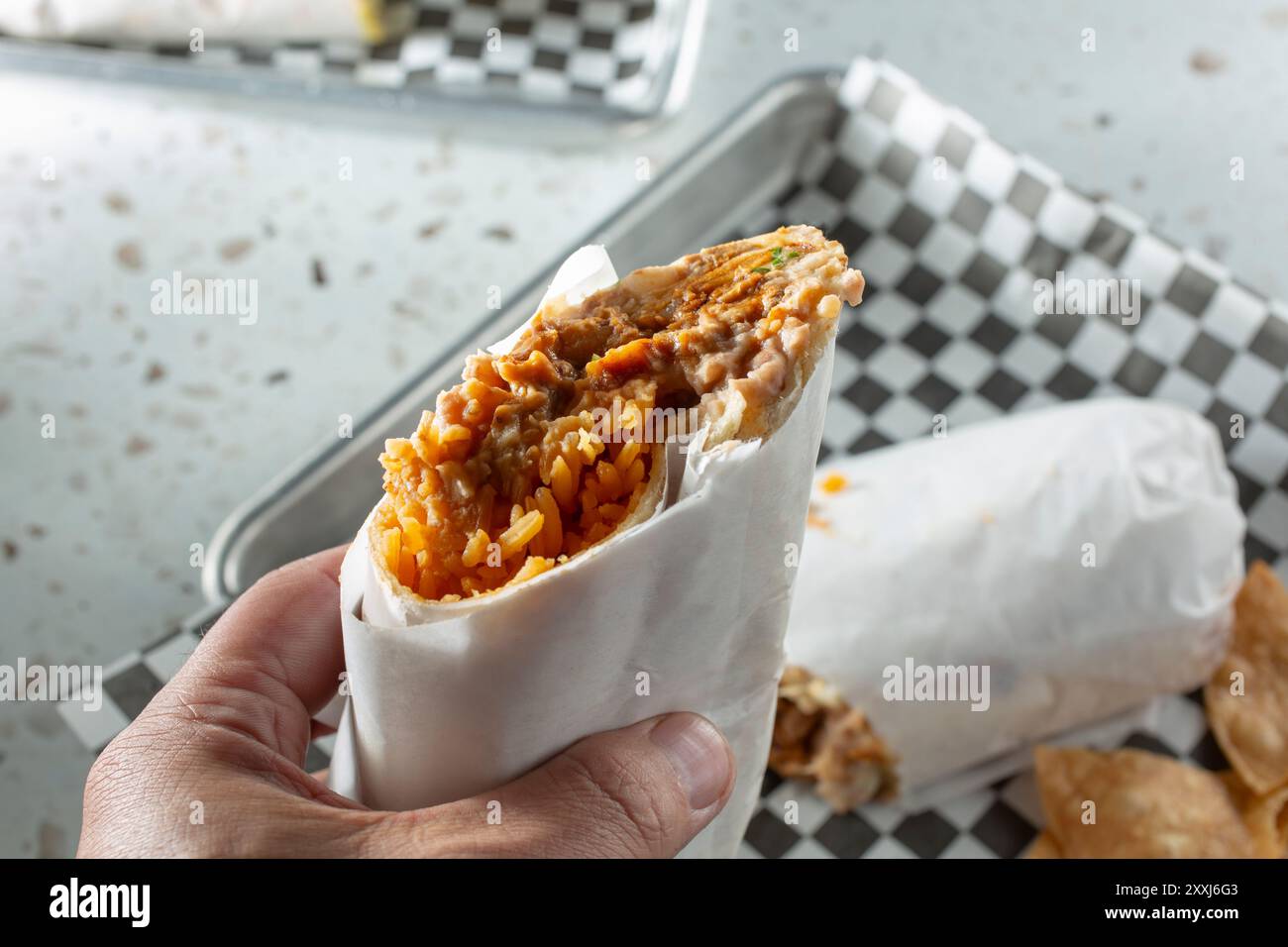 A view of a hand holding an al pastor burrito Stock Photo - Alamy