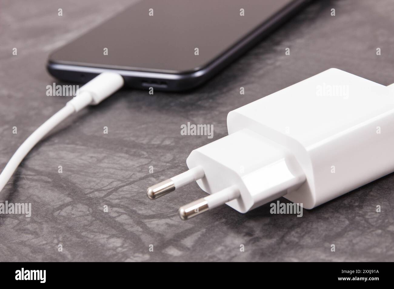 Black smartphone with connected white plug of charger. Telephone ...