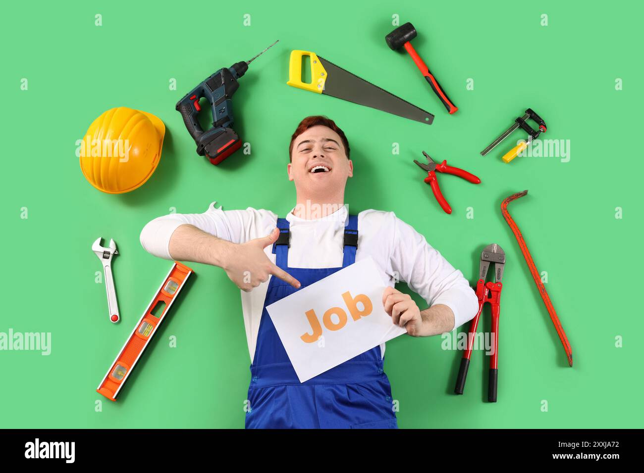 Male builder pointing at paper with word JOB and work tools on green ...