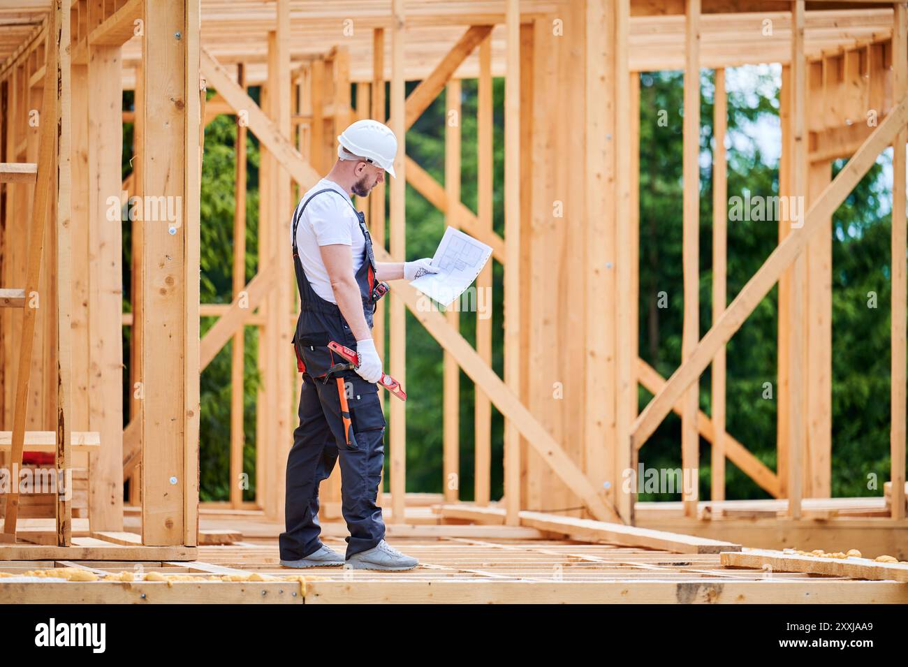 Engineer constructing wooden two-story frame house. Bearded man in ...