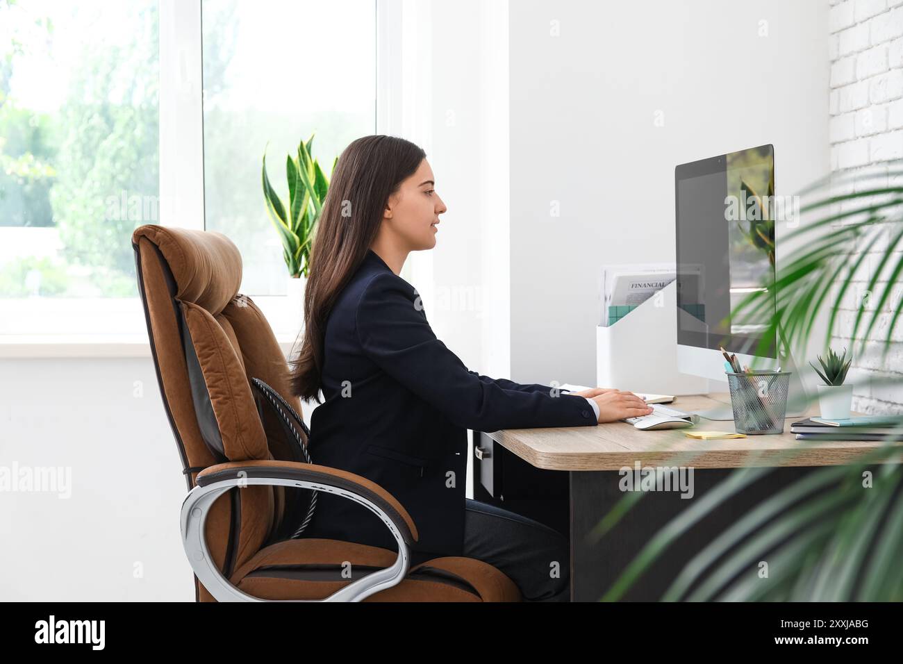 Female office worker using modern computer at workplace in light office ...