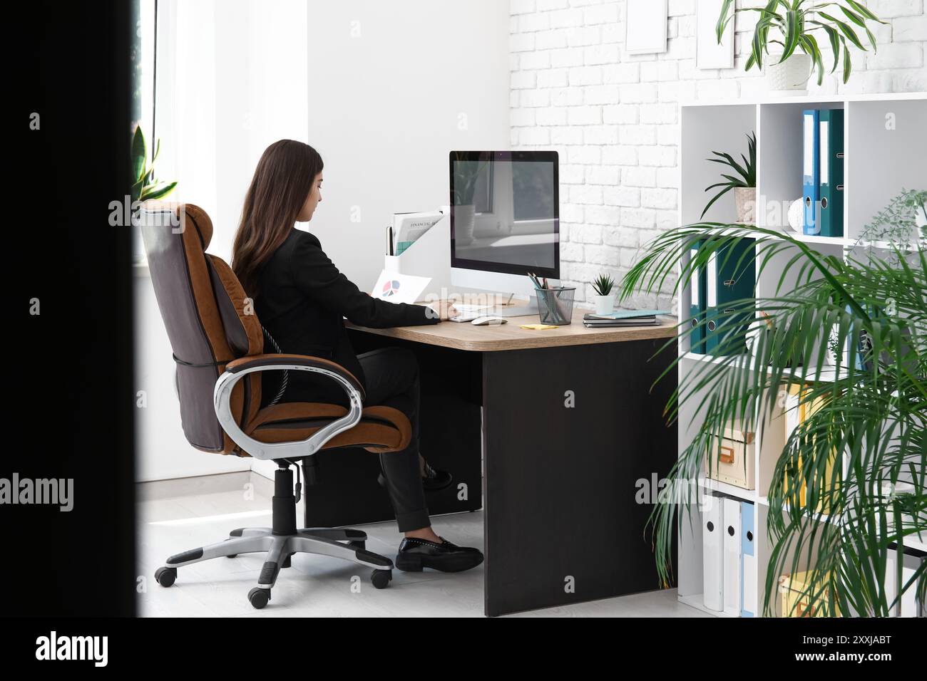Female office worker using modern computer at workplace in light office ...