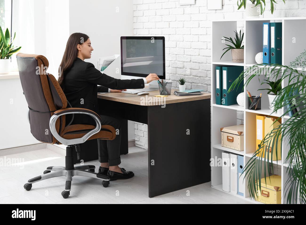Female office worker using modern computer at workplace in light office ...