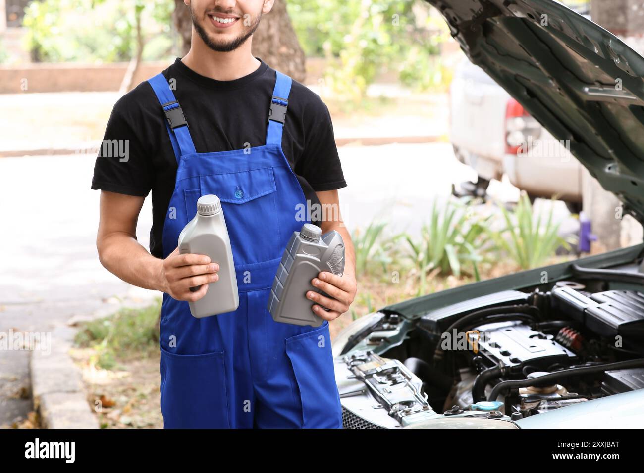 Male mechanic with bottles of car oil outdoors Stock Photo - Alamy
