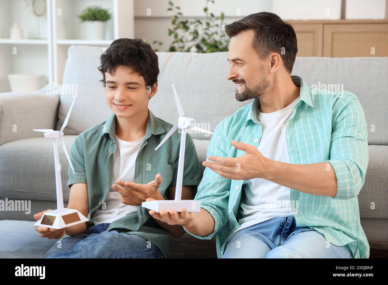 Teenage boy and his father with wind turbine models talking at home ...