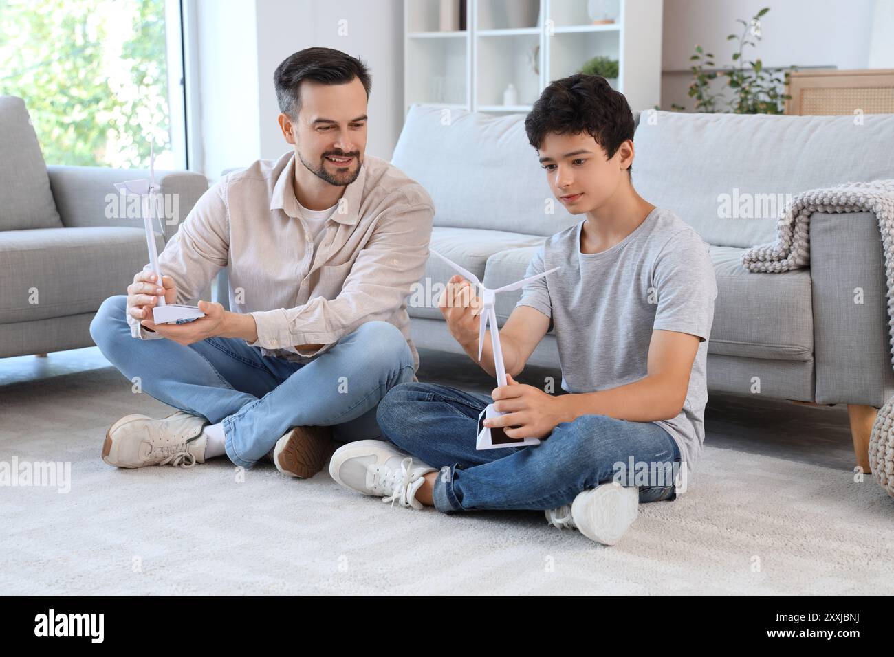 Teenage boy and his father with wind turbine models sitting on floor at ...