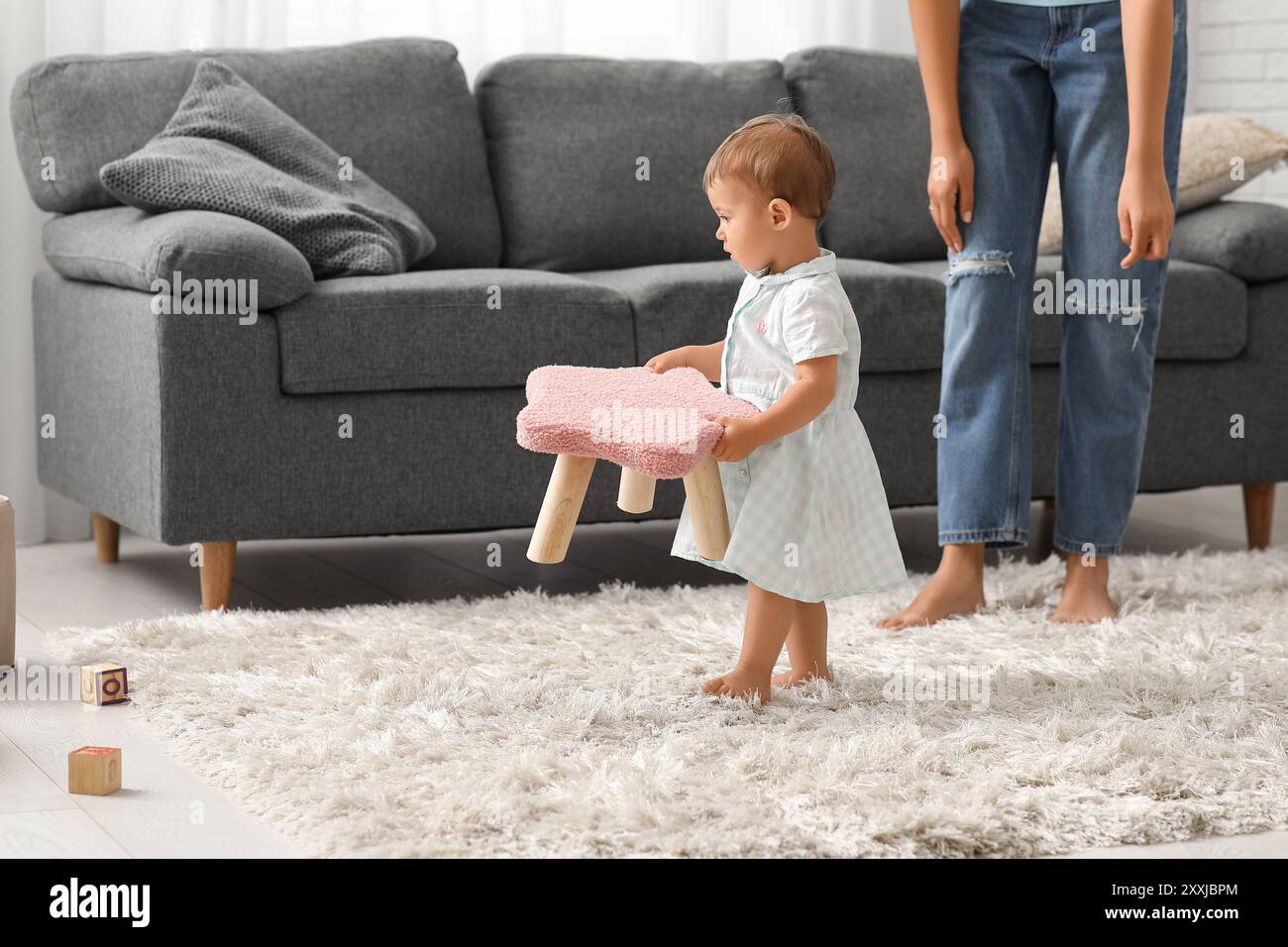 Little baby girl learning to walk with stool and mother at home Stock ...