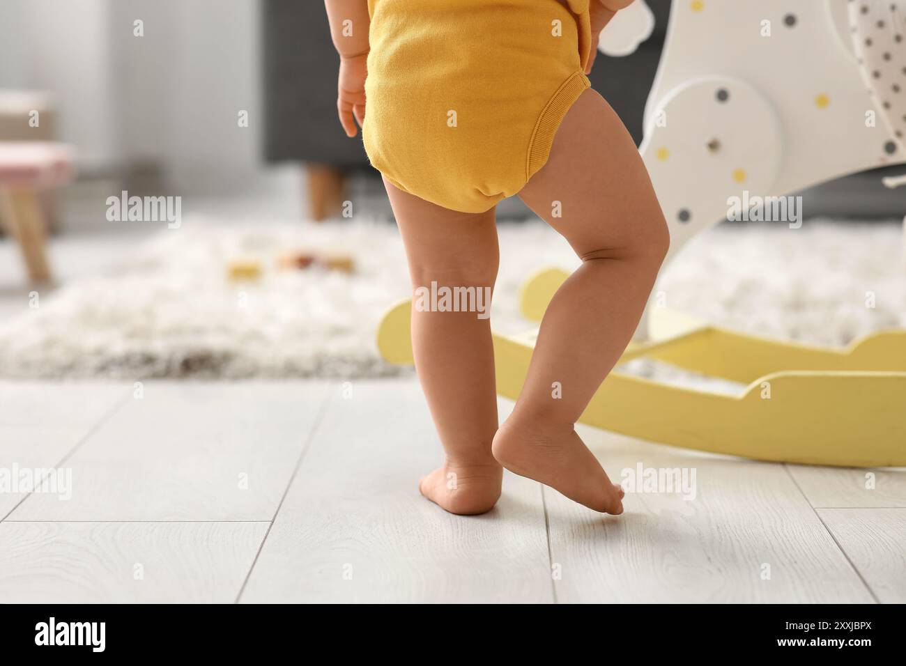 Little baby girl learning to walk at home, back view Stock Photo - Alamy
