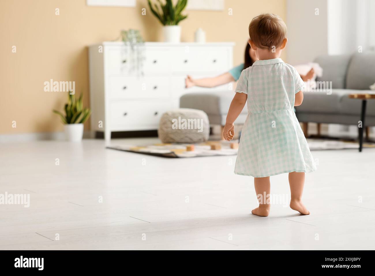 Little baby girl learning to walk and mother at home, back view Stock ...