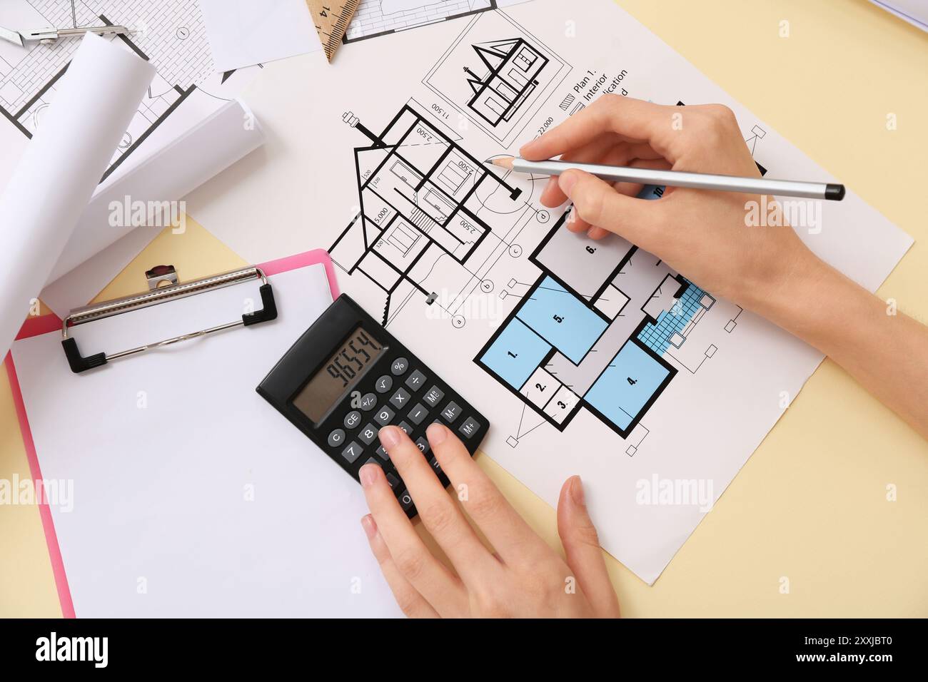 Female architect with house plan using calculator on yellow background ...