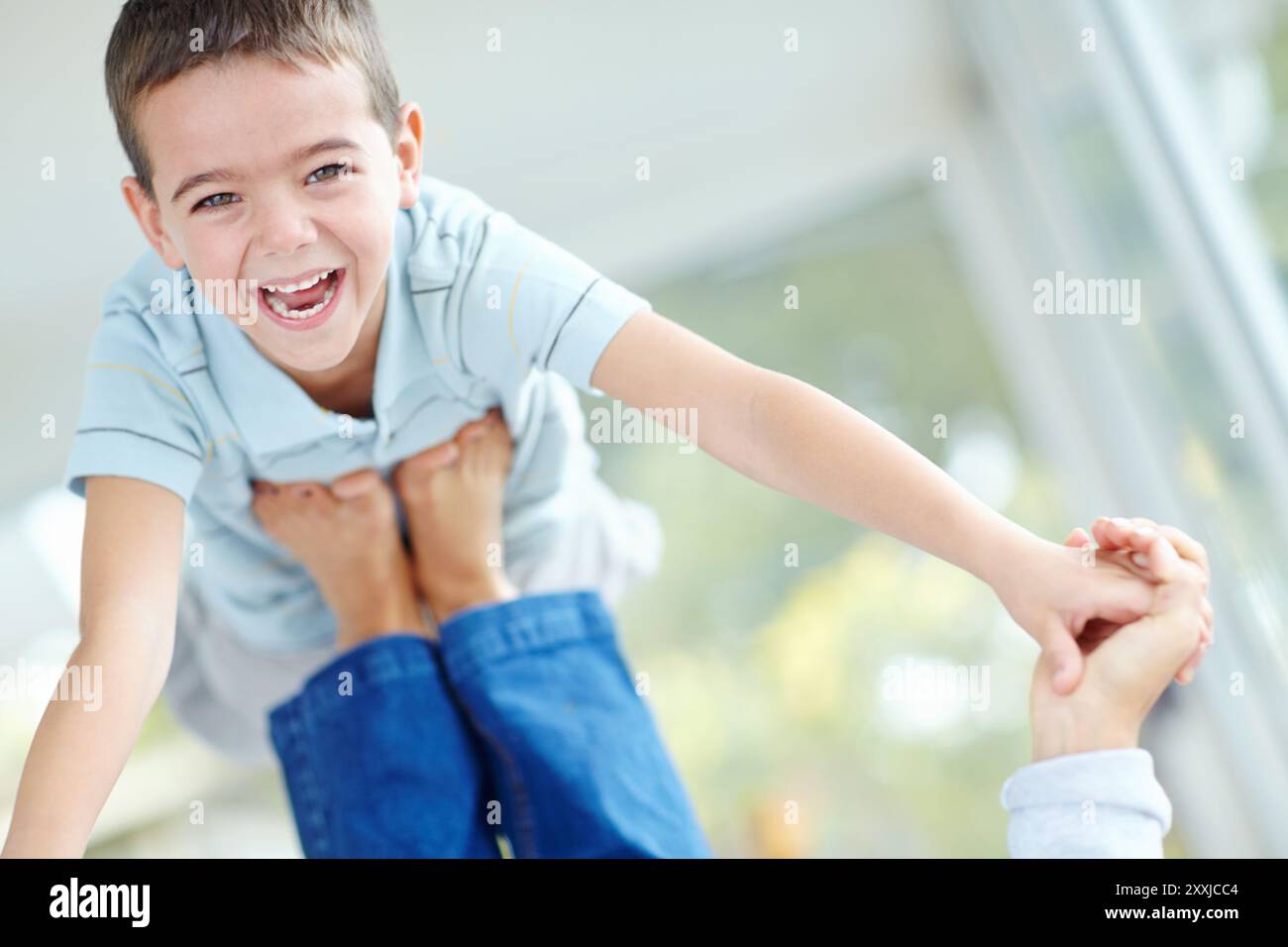 Portrait, parent and lifting excited child in home with feet for game ...