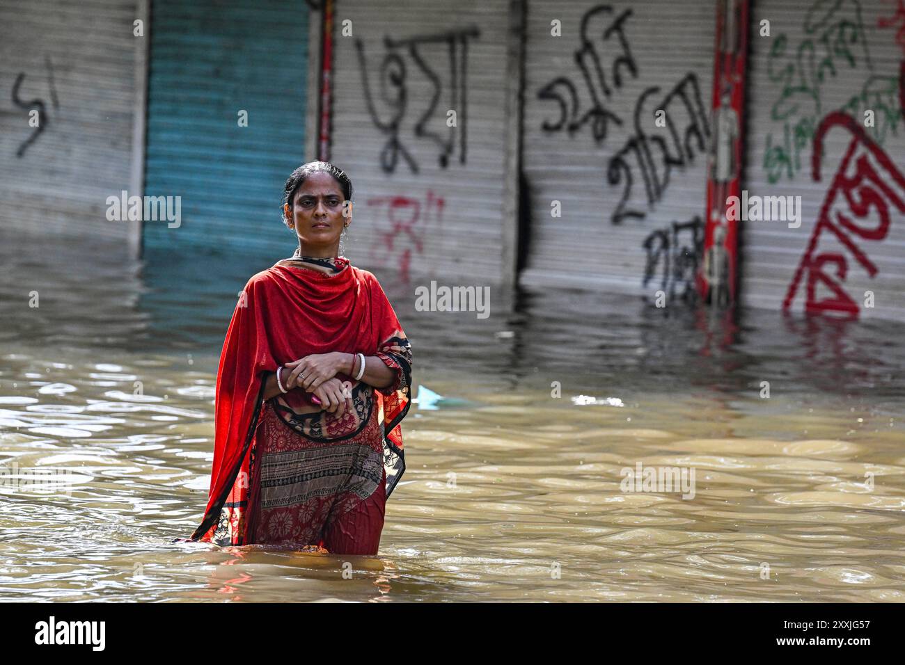 Dhaka, Bangladesh. 24th Aug, 2024. A woman wades through floodwater in ...