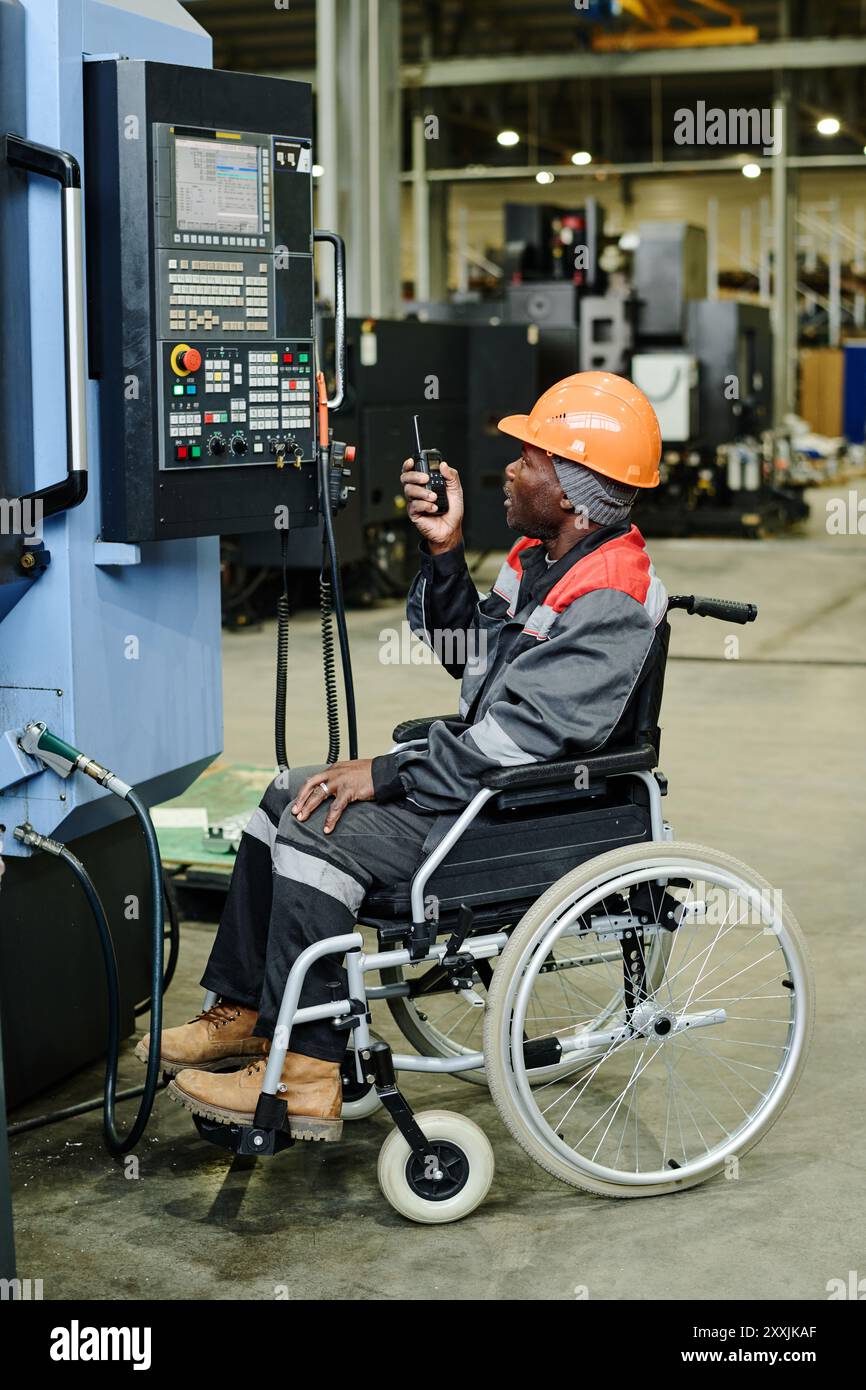 Disabled factory worker operating advanced industrial equipment from ...