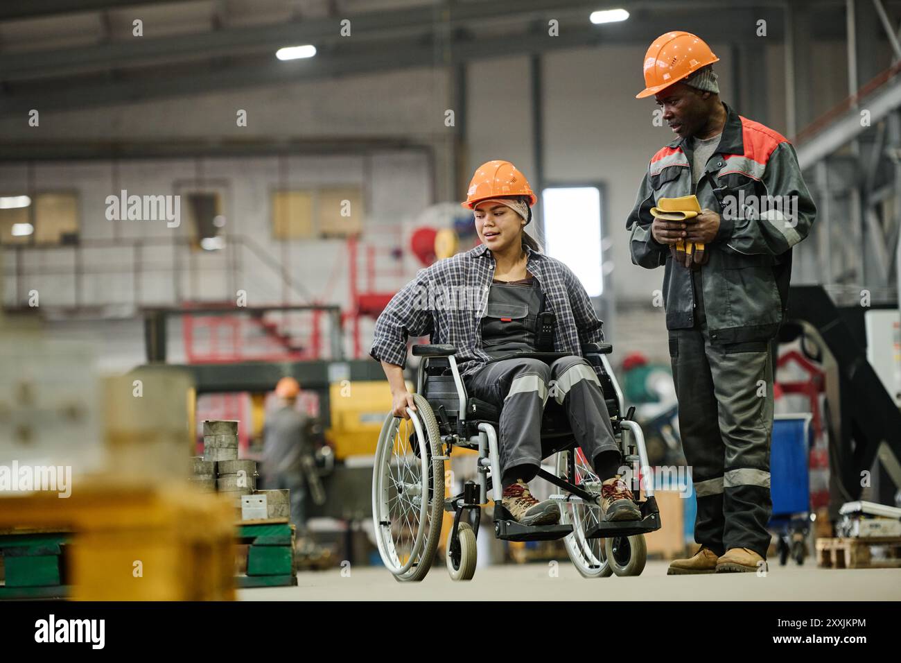 Wheelchair-using worker conversing with a colleague in an industrial ...