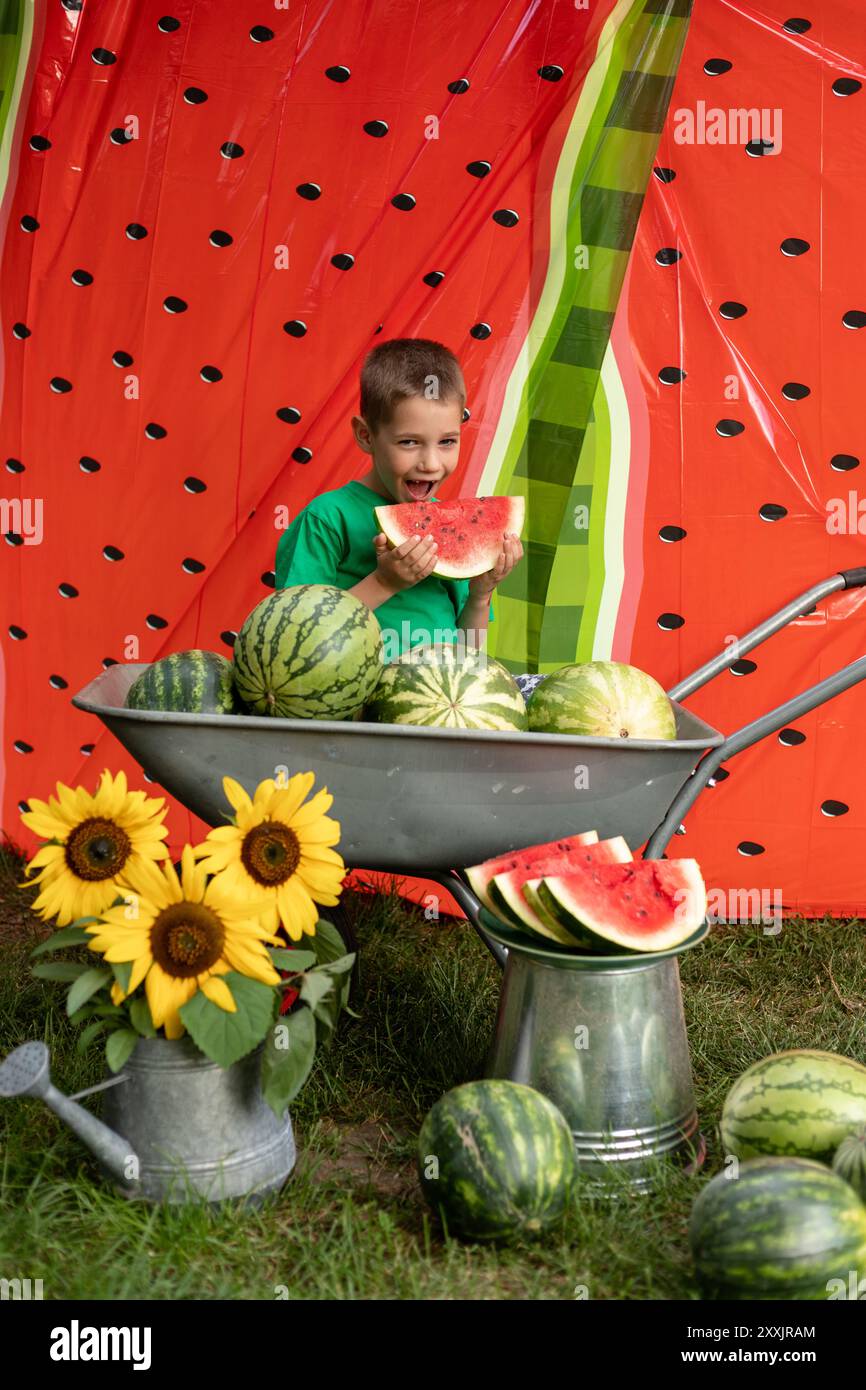 A boy eats a watermelon. A wheelbarrow with watermelons. Summer ...
