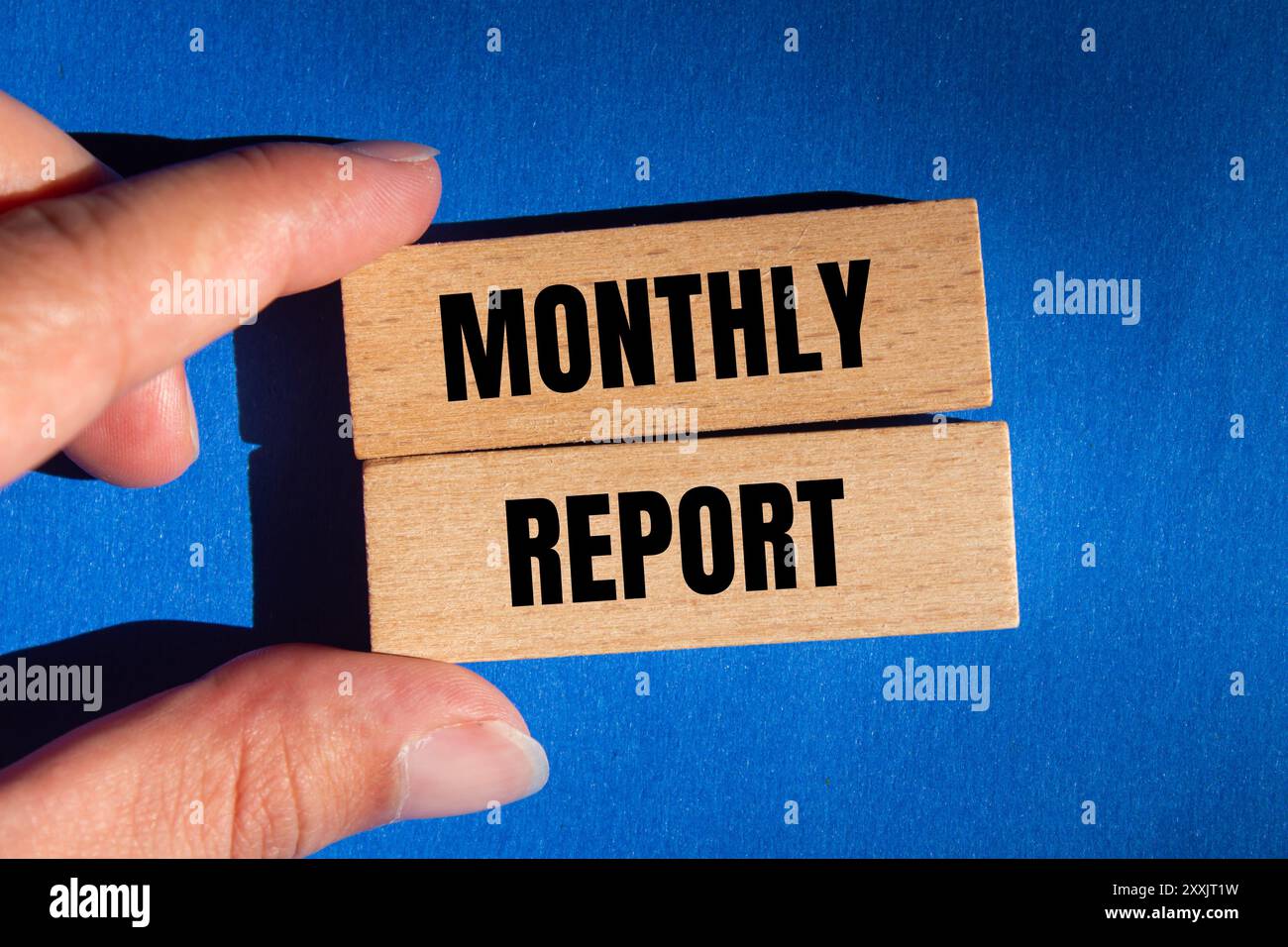 Monthly report message written on wooden blocks on blue background. Conceptual monthly report ...