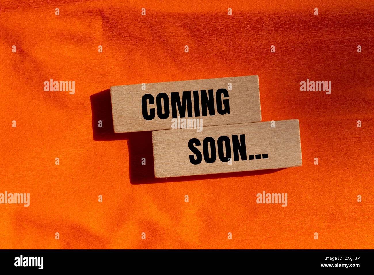 Coming soon message written on wooden blocks with orange background ...
