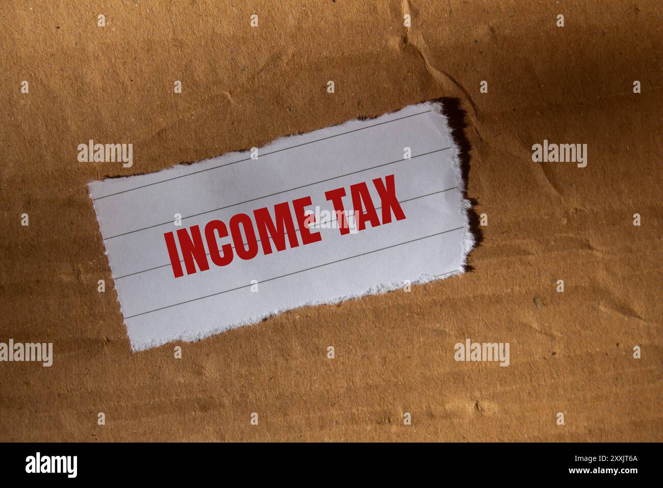 Income tax message written on ripped torn white paper piece with ...