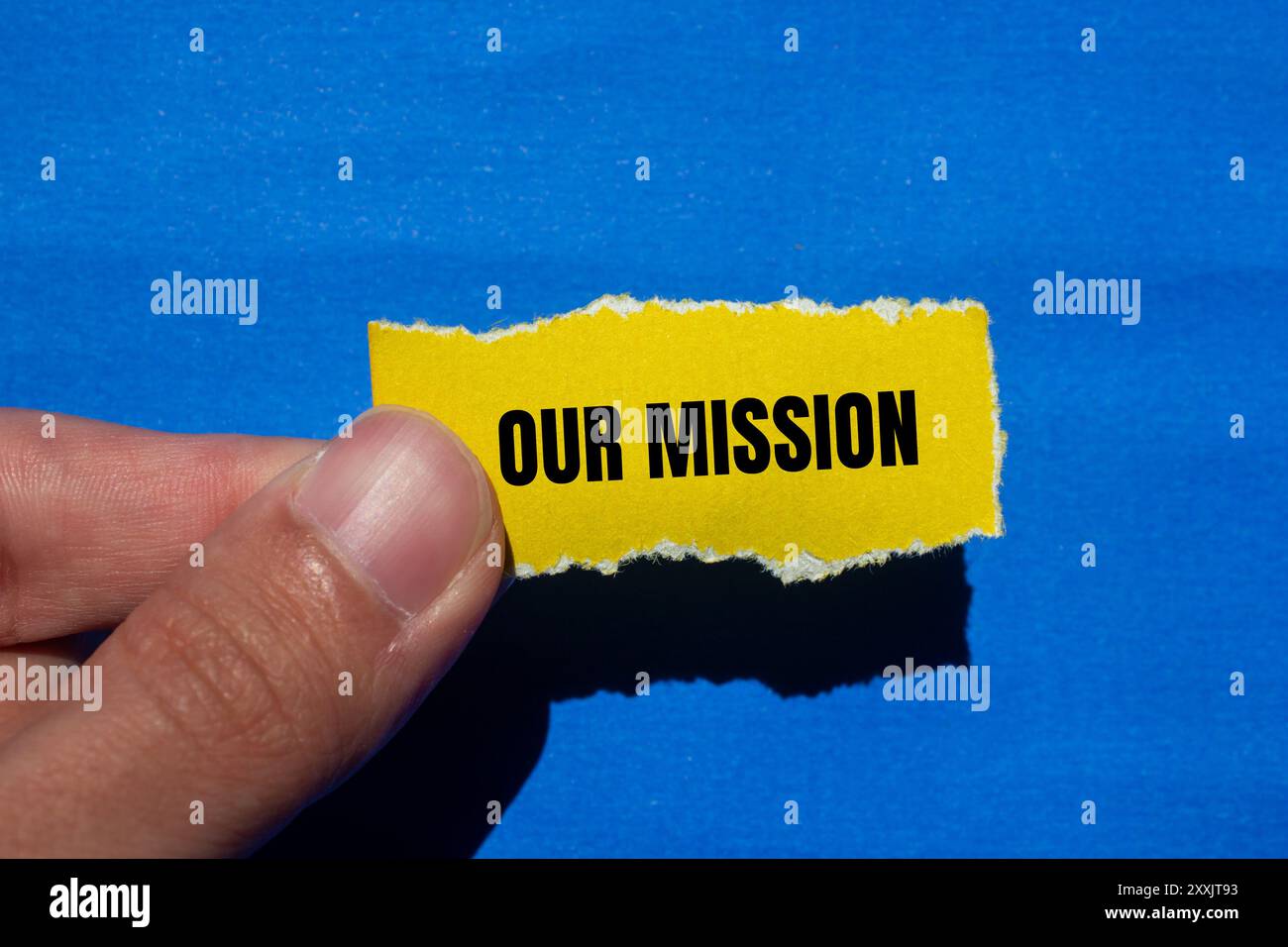 Our mission message written on ripped torn yellow paper with blue ...