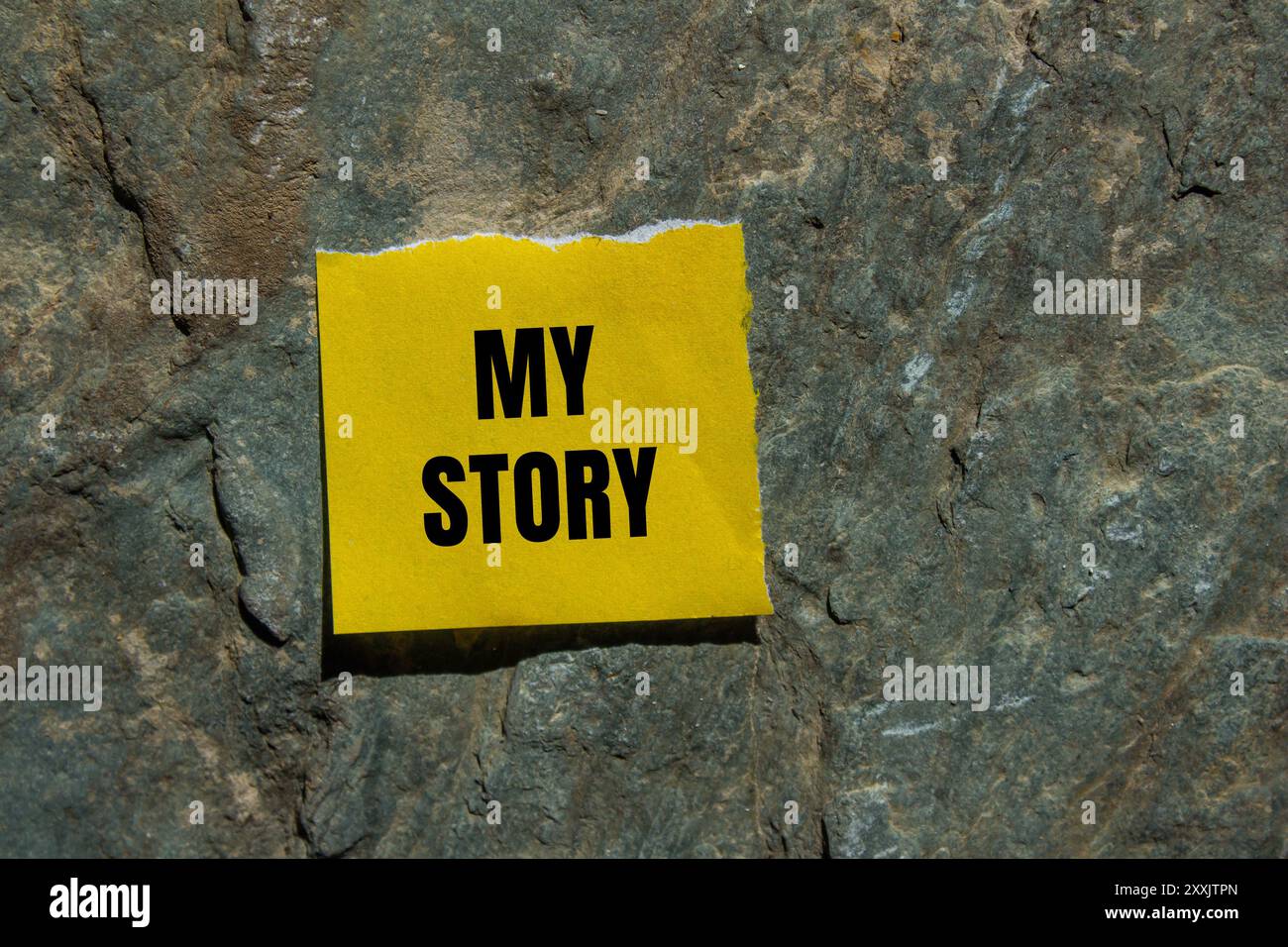 My story message written on ripped yellow torn paper piece with stone background. Conceptual my ...