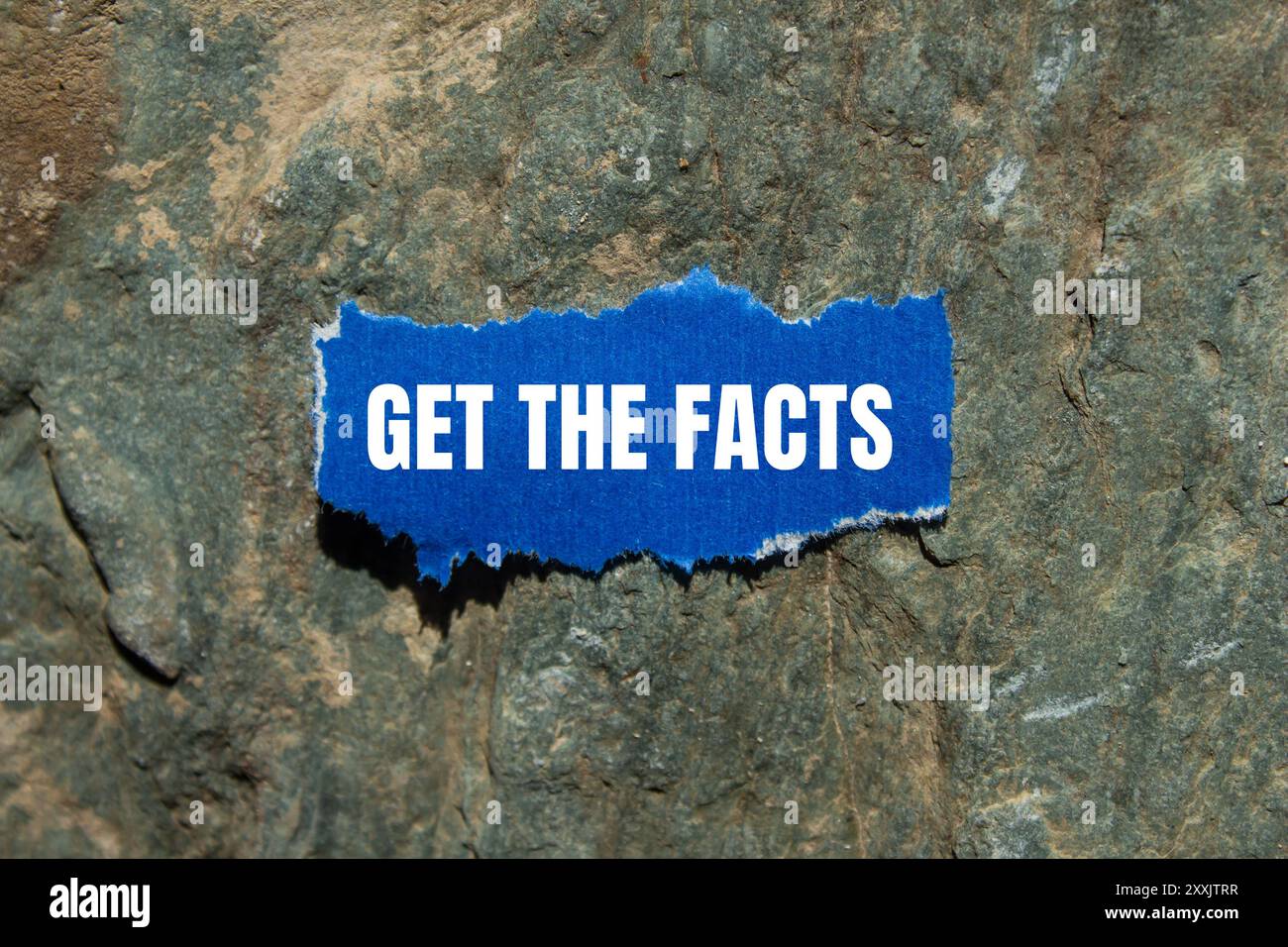 Get the facts message written on ripped torn blue paper piece with stone background. Conceptual ...