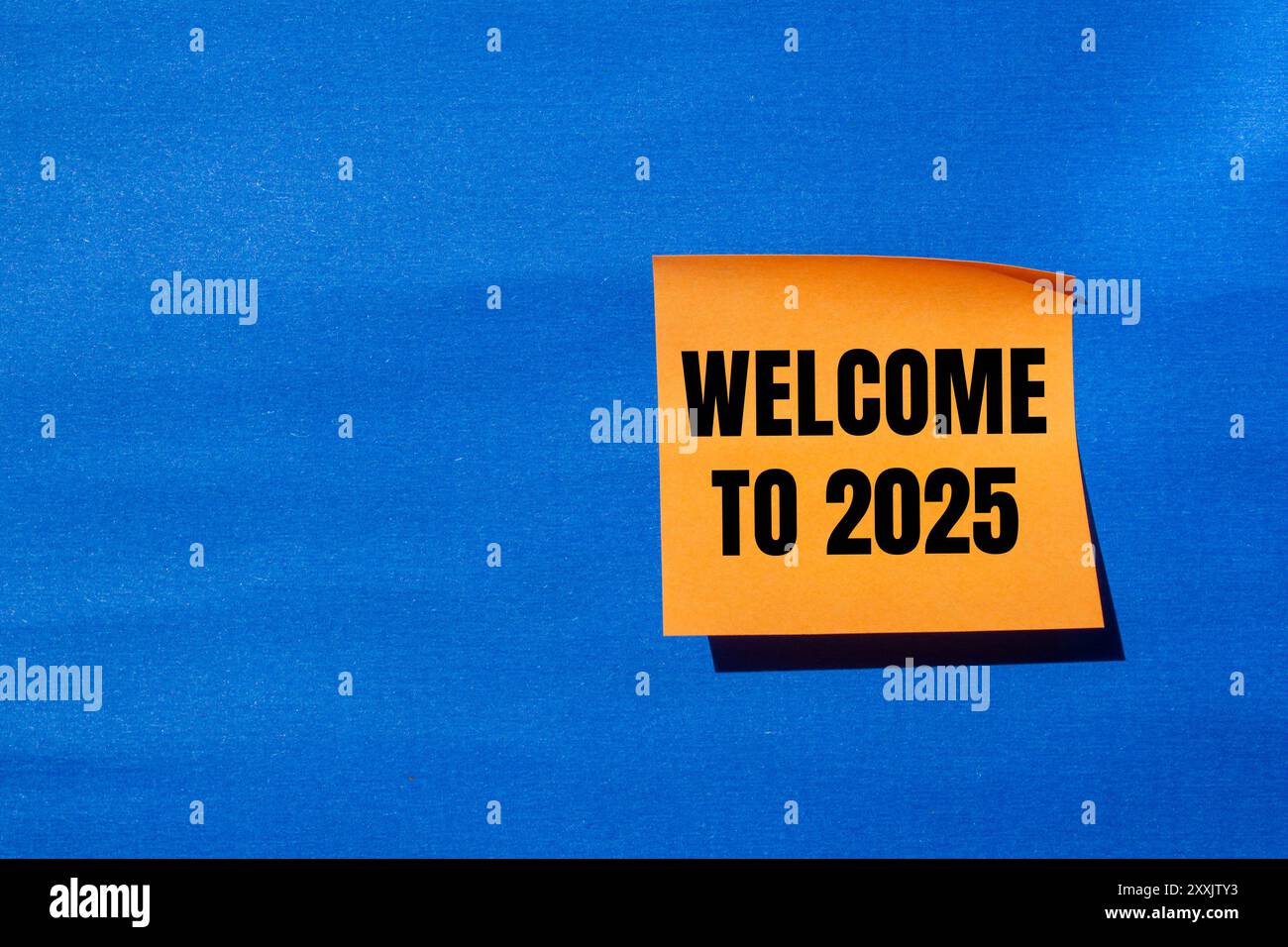 Welcome to 2025 message written on orange paper with blue background ...