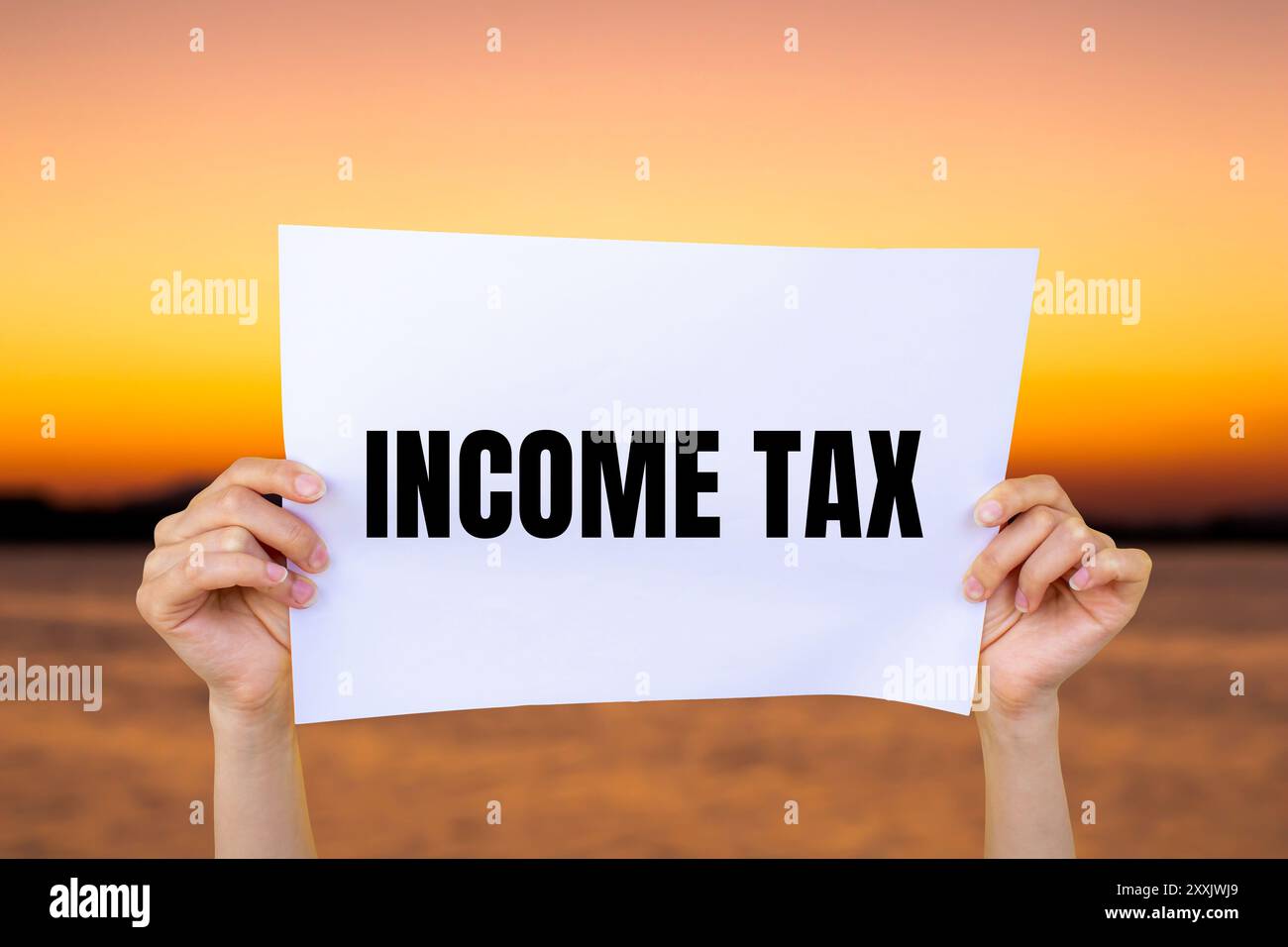 Income tax message written on white paper with blurry lake background ...