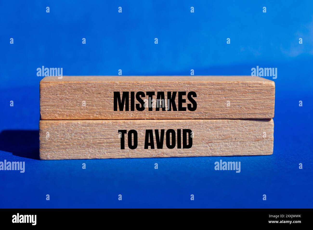 Mistakes to avoid message written on wooden blocks with blue background ...