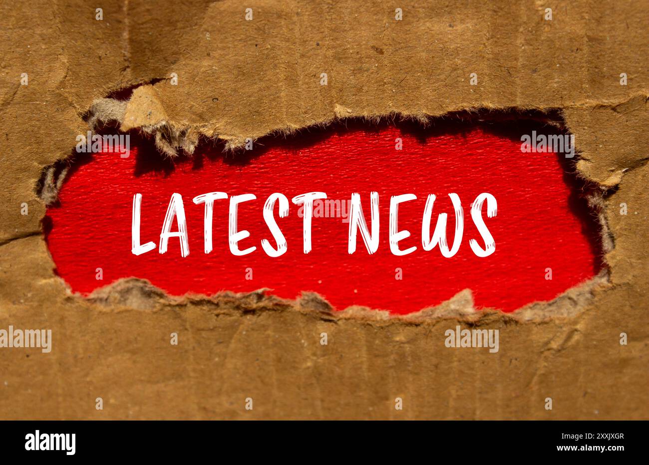 Latest news message written on torn cardboard paper with red background ...