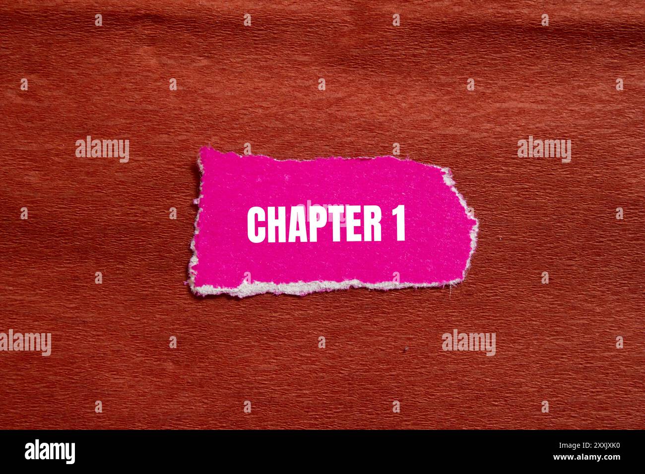 Chapter 1 message written on ripped torn pink paper piece with brown background. Conceptual ...