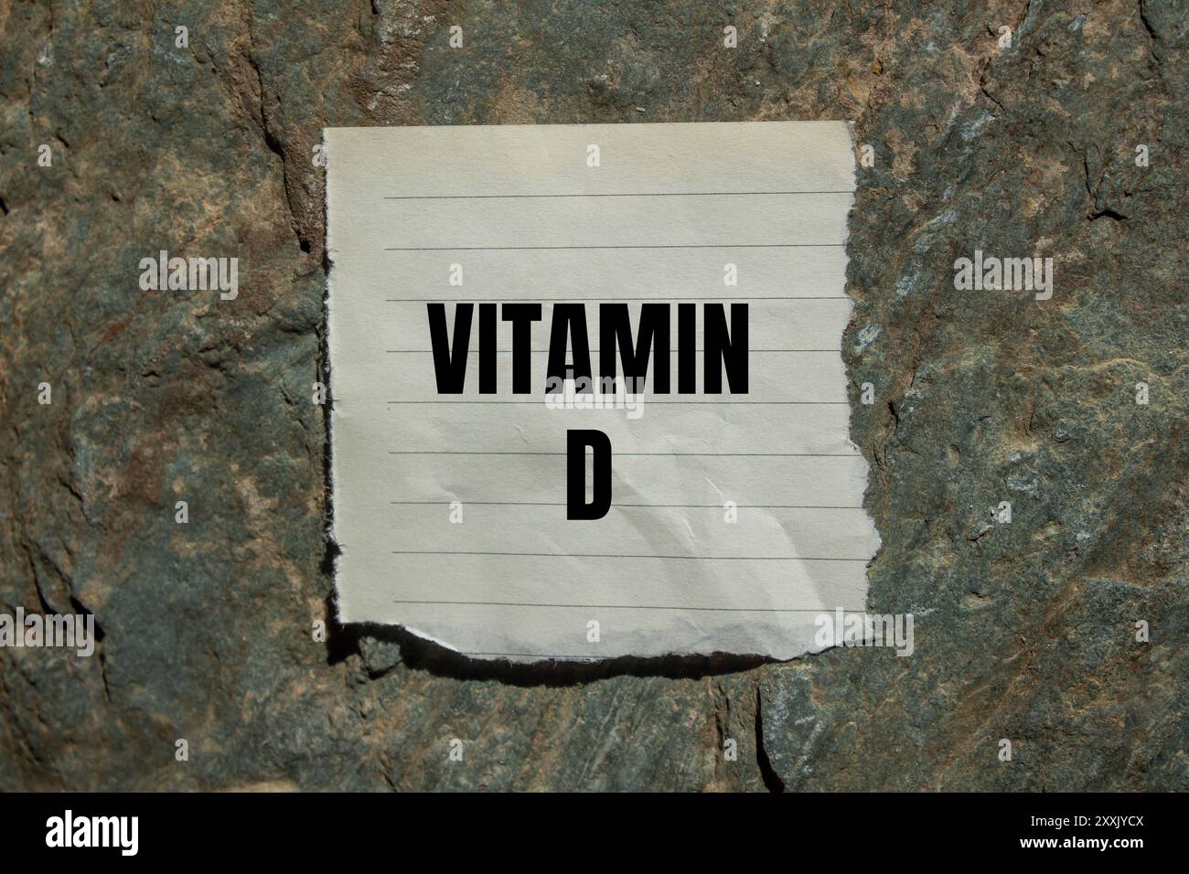 Vitamin d message written on ripped torn paper piece with stone background. Conceptual vitamin d ...