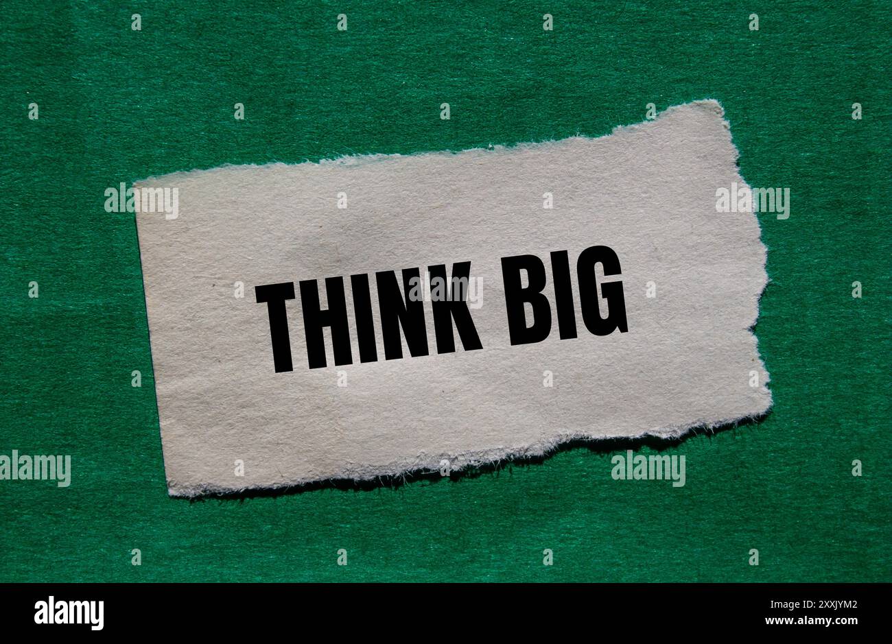 Think big message written on ripped torn paper piece with green ...