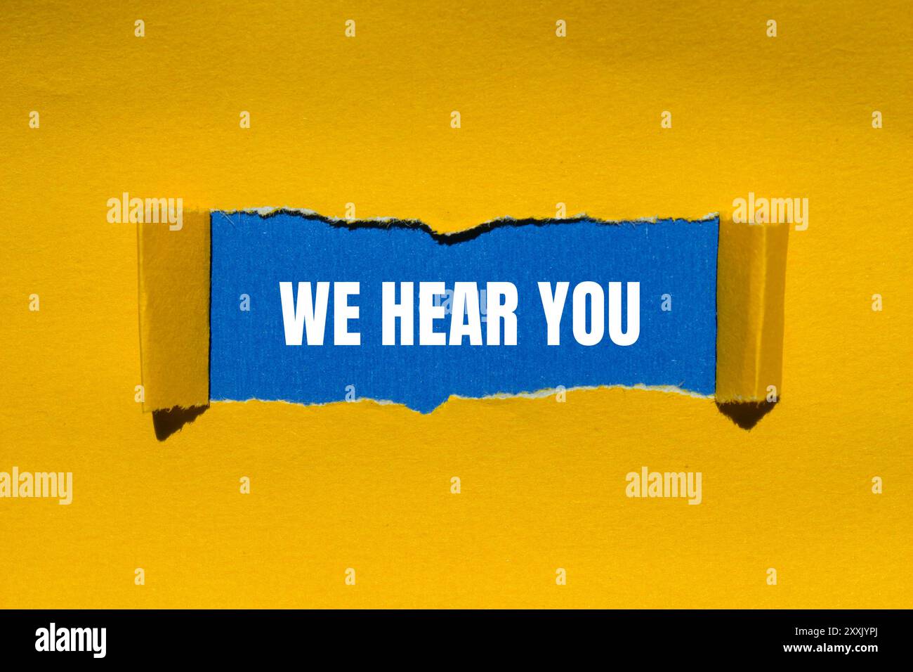 We hear you message written on ripped torn yellow paper with blue background. Conceptual we hear ...