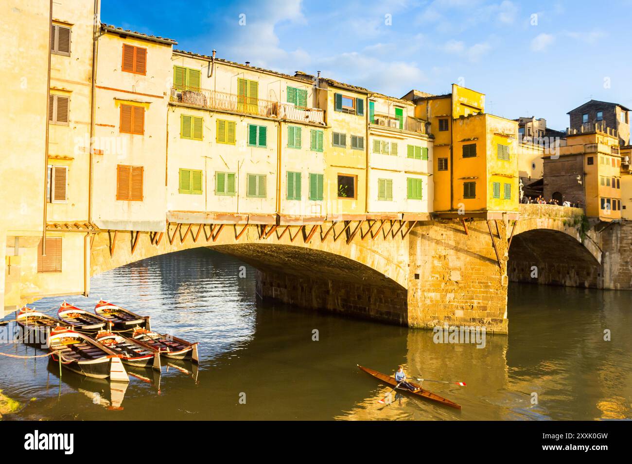 Row boat going under the historic Ponte Vecchio bridge in Florence ...