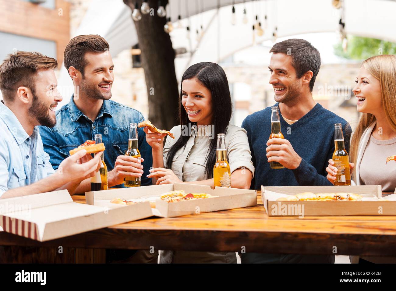 Spending great time with friends. Group of joyful young people eating ...