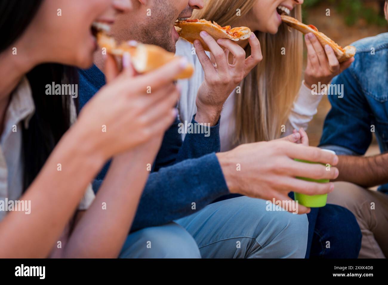 Time for pizza! Group of young people eating pizza while sitting ...