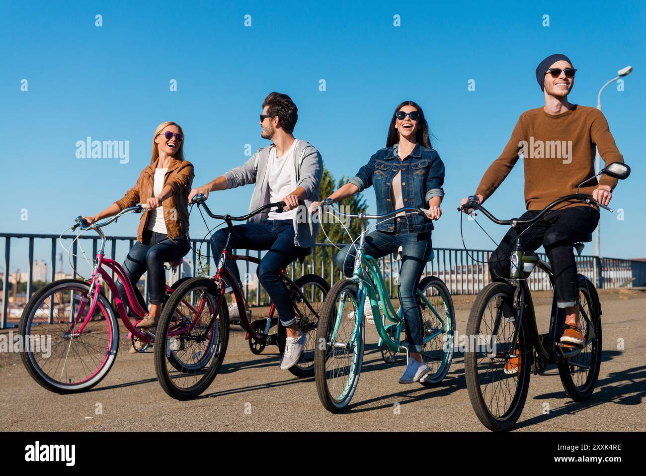Good day for a ride. Full length of four young people riding their ...