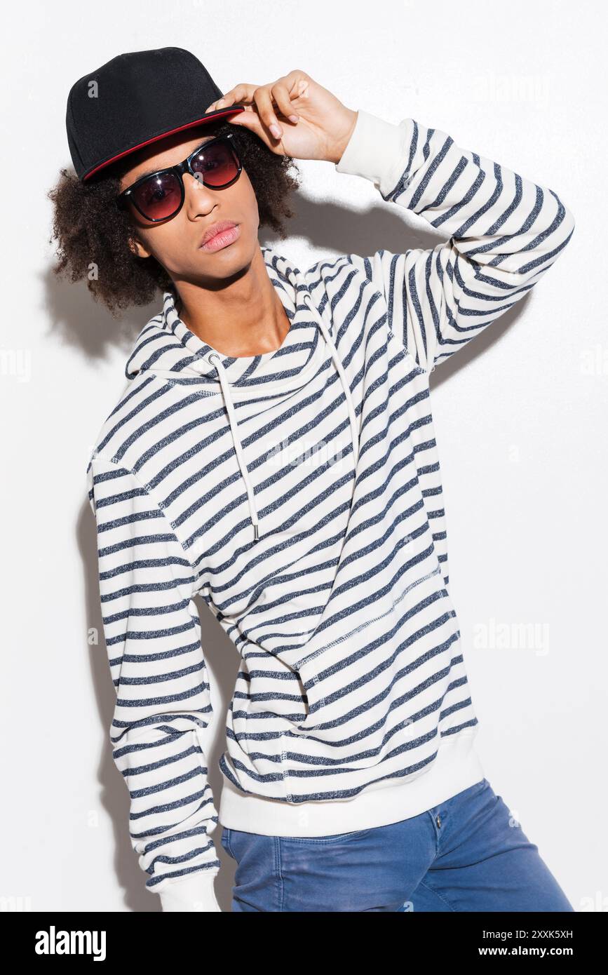 Well hello! Handsome young African man adjusting his cap while standing ...