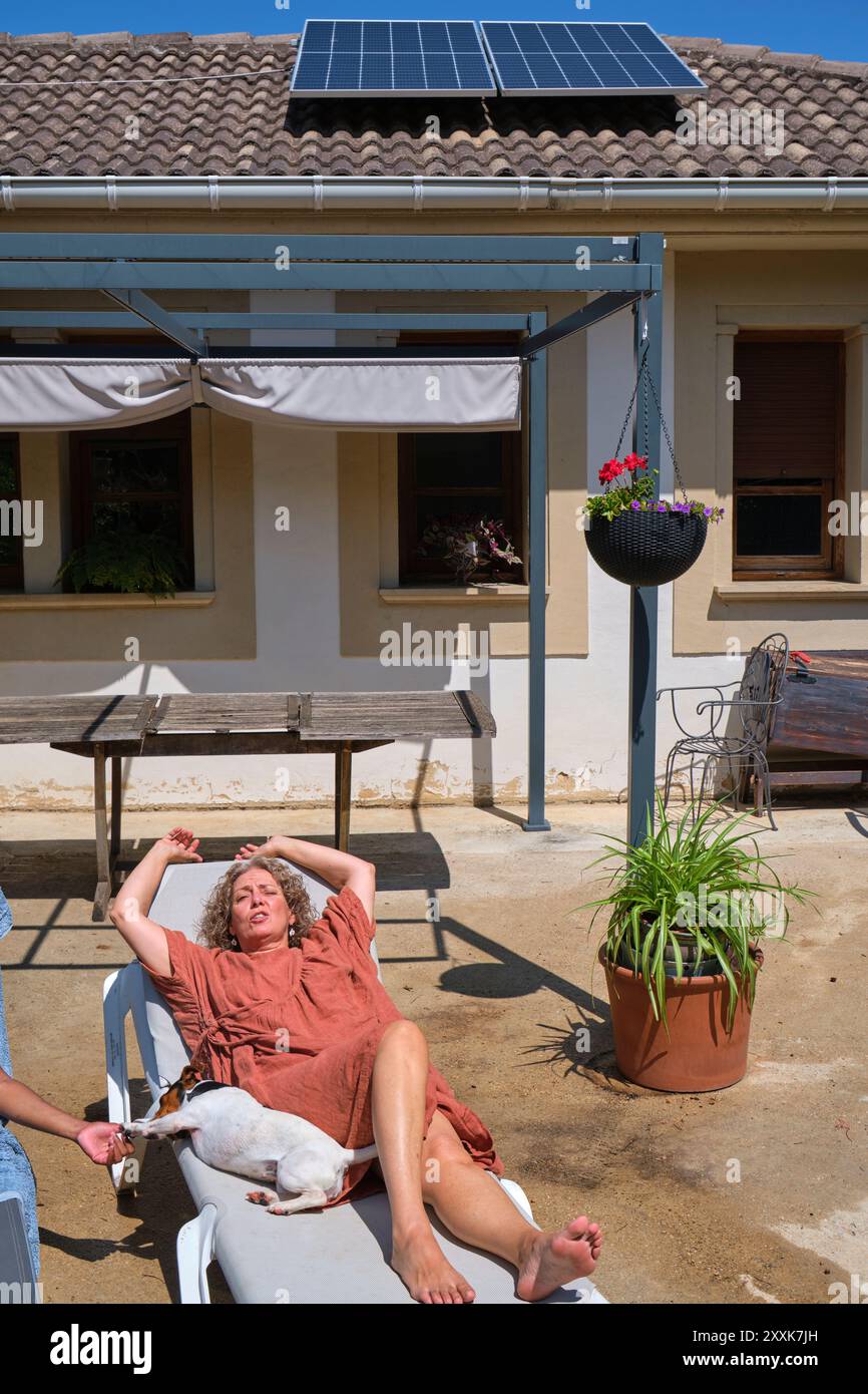 Woman sunbathing with a small dog on a patio Stock Photo - Alamy