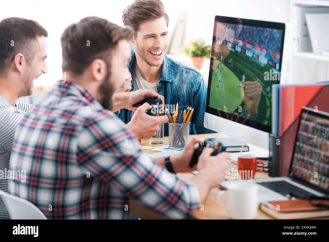 Testing new game. Three young men playing computer games while sitting ...