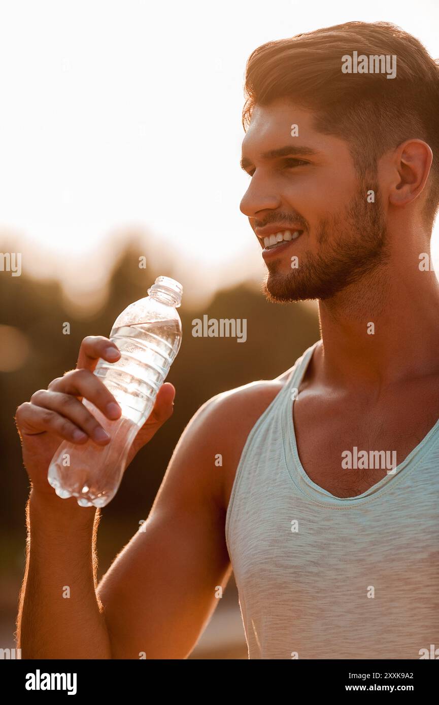 Water is a key to good workout. Handsome young muscular man holding a ...