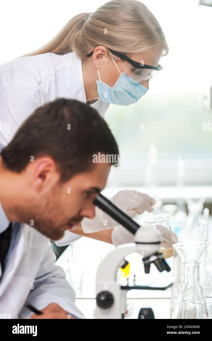 Scientists at work. Side view of male scientist using microscope while ...