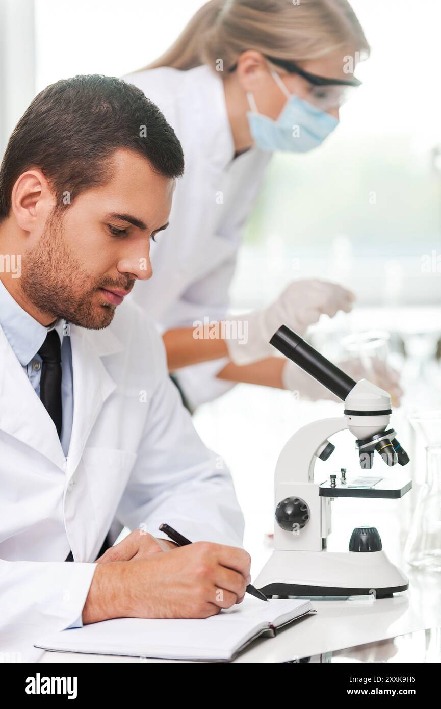 Our goal is to find the cure. Side view of male scientist writing in ...