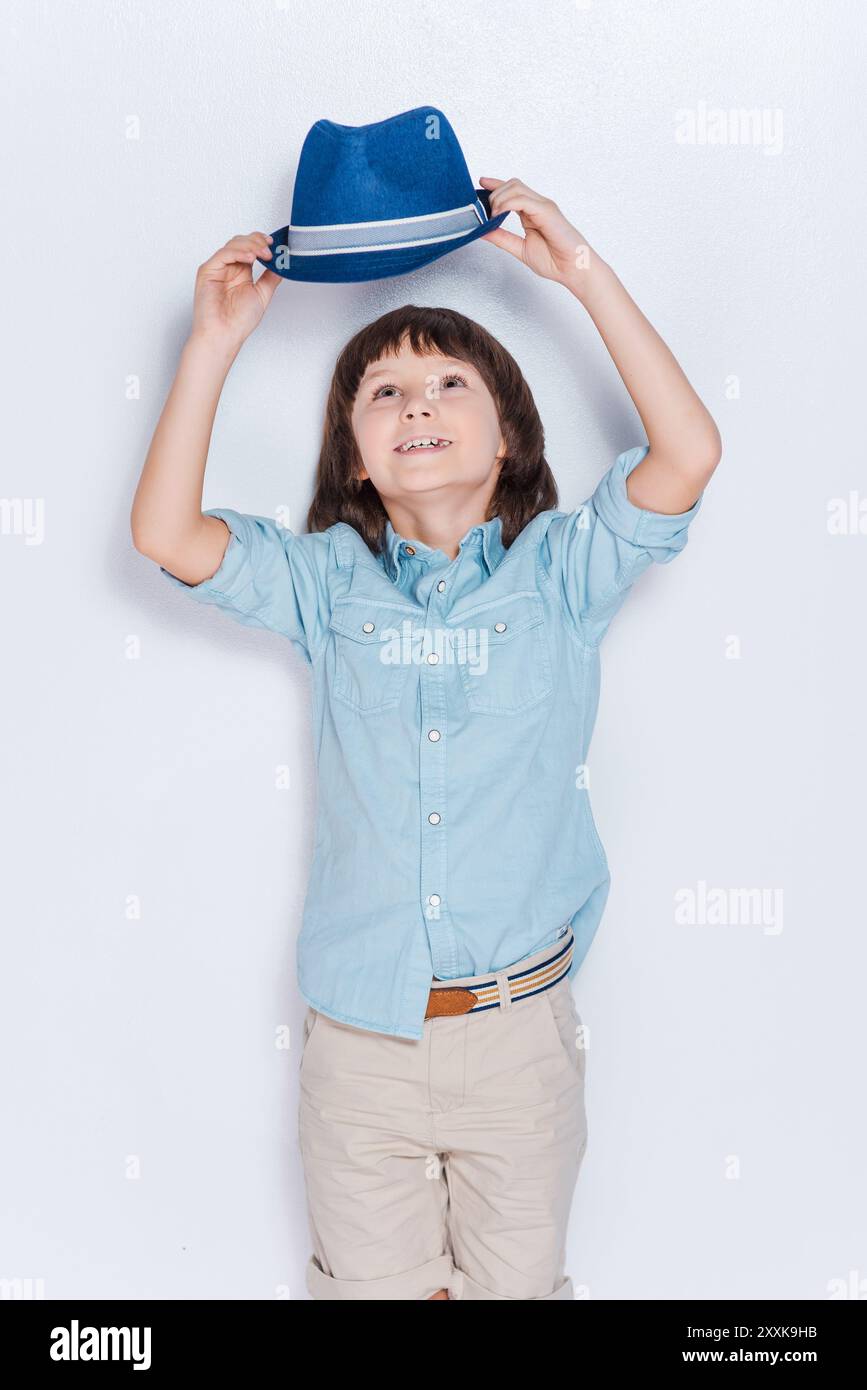 My favorite hat. Happy little boy holding hat over his head and looking ...